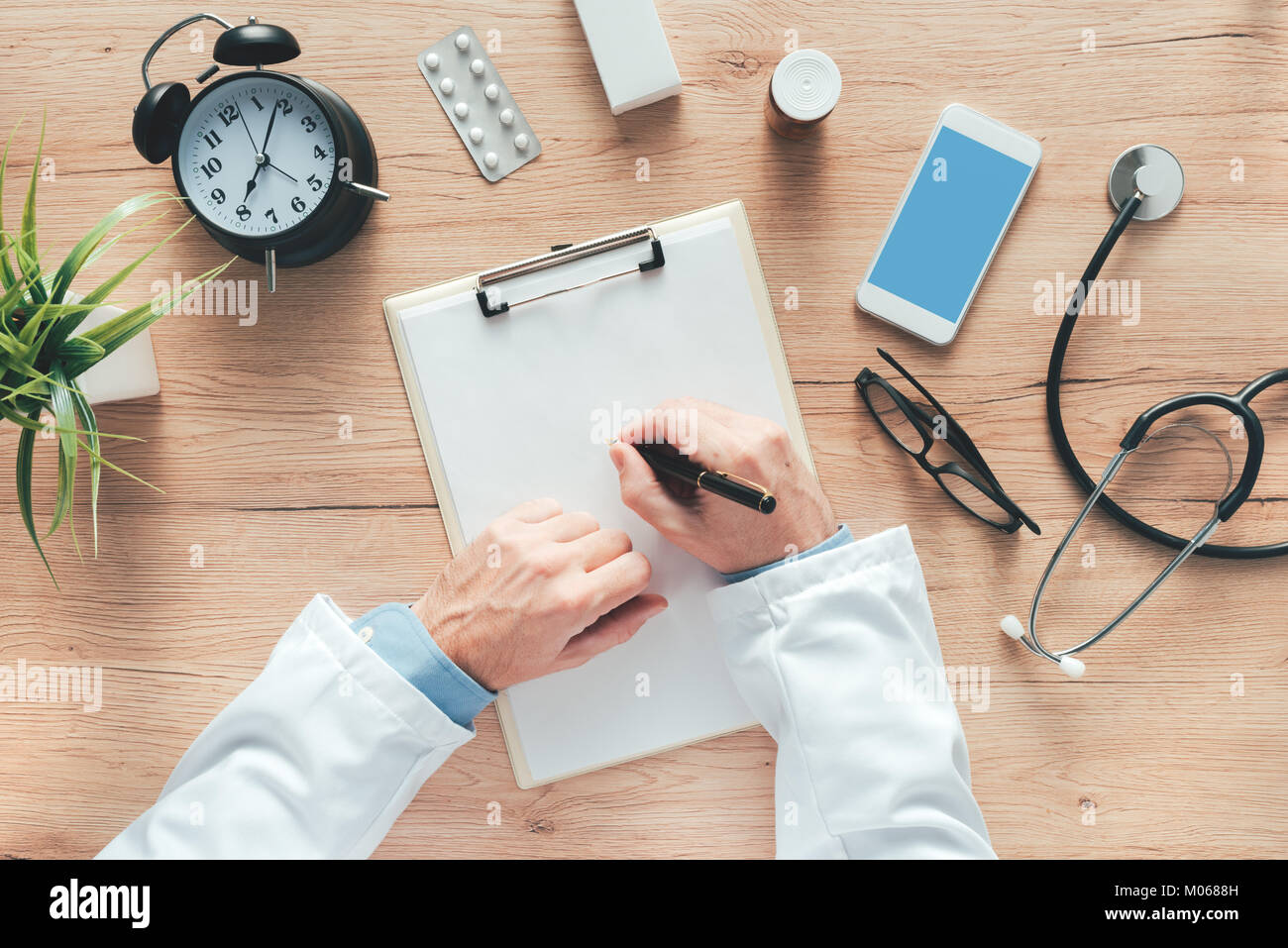 Overhead view of male doctor writing notes, patient's medical history ...