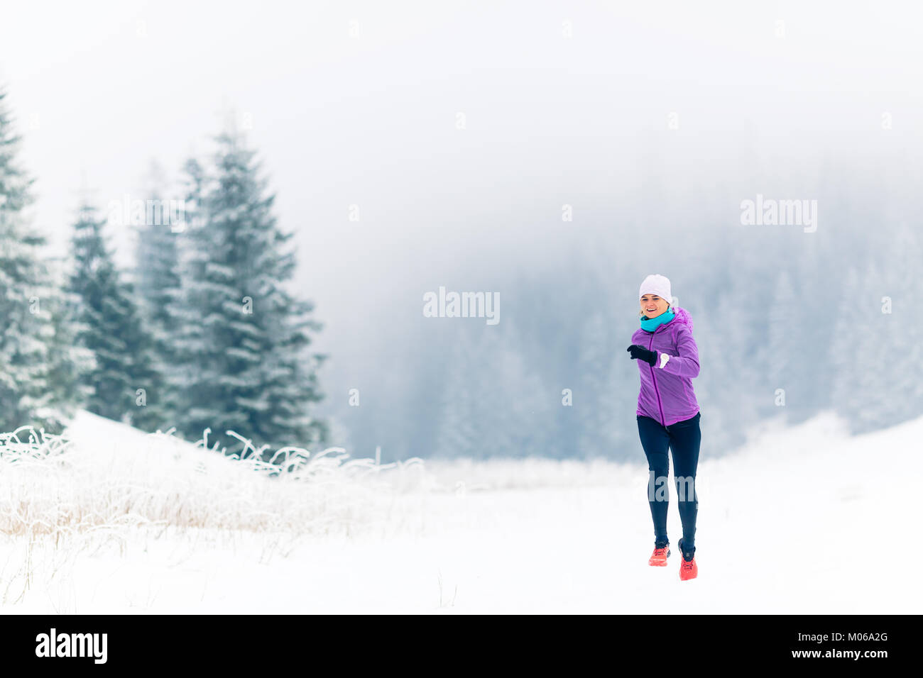 Woman trail running in mountains on snow footpath, winter day. Sport ...