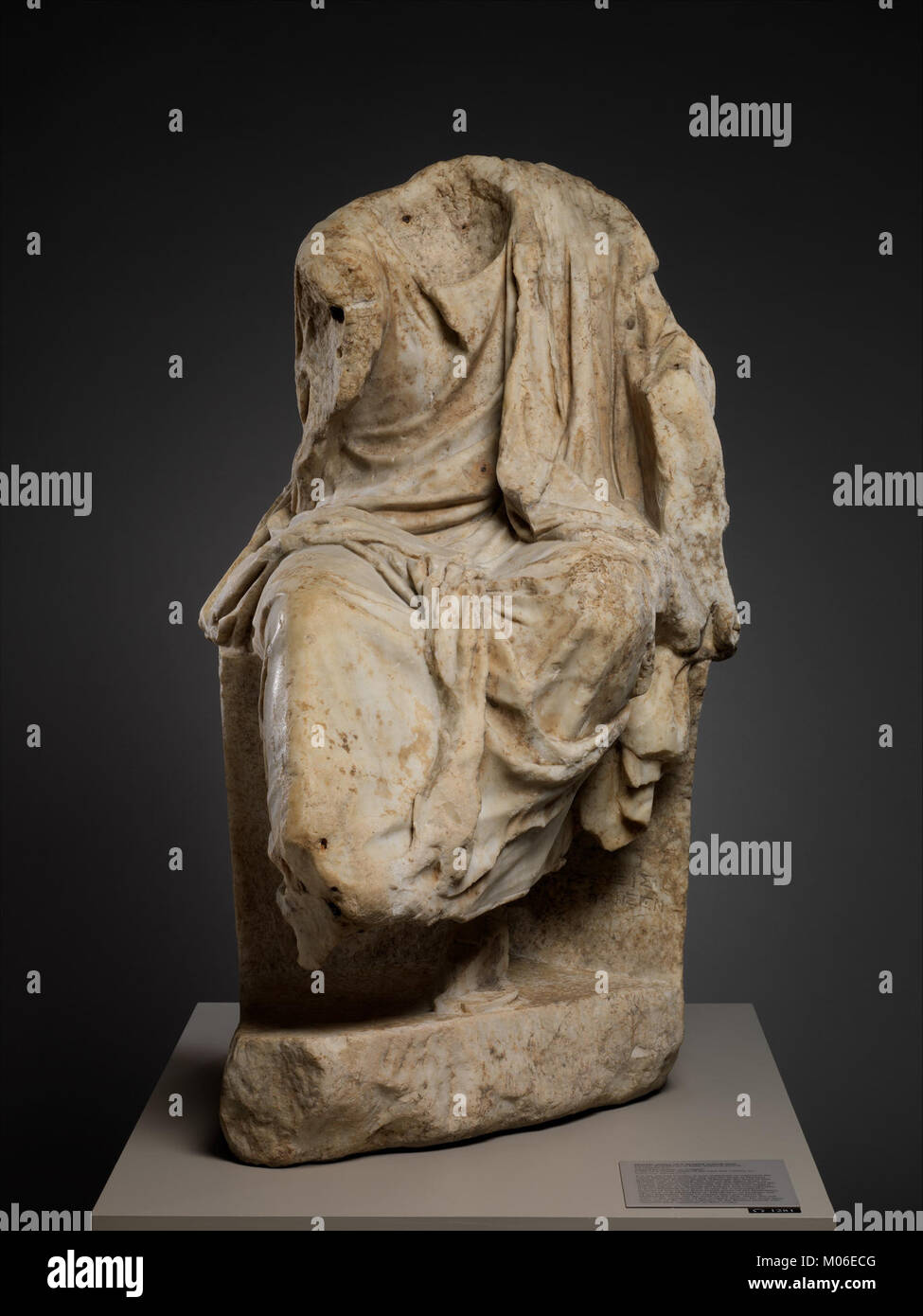 A marble statue depicting a seated man draped in a flowing garment. The ...