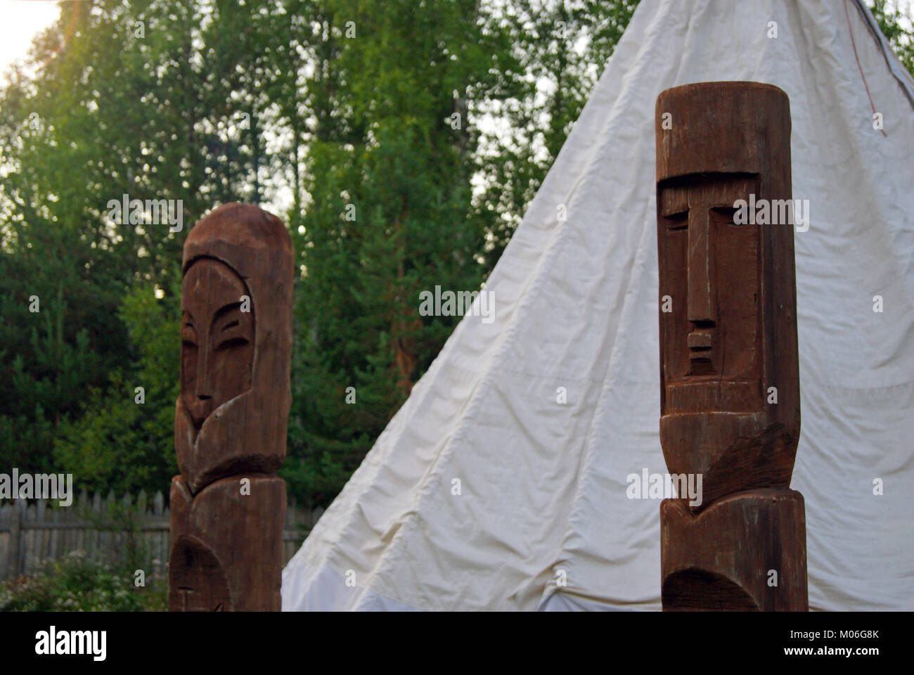 two heathen wooden totems in front of a traditional tent (chum or tipi ...