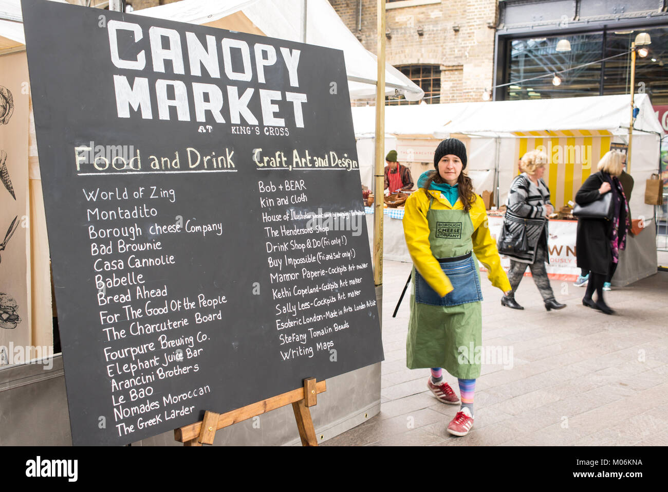 Stall owner walking in front of a billboard promoting the Canopy Market ...