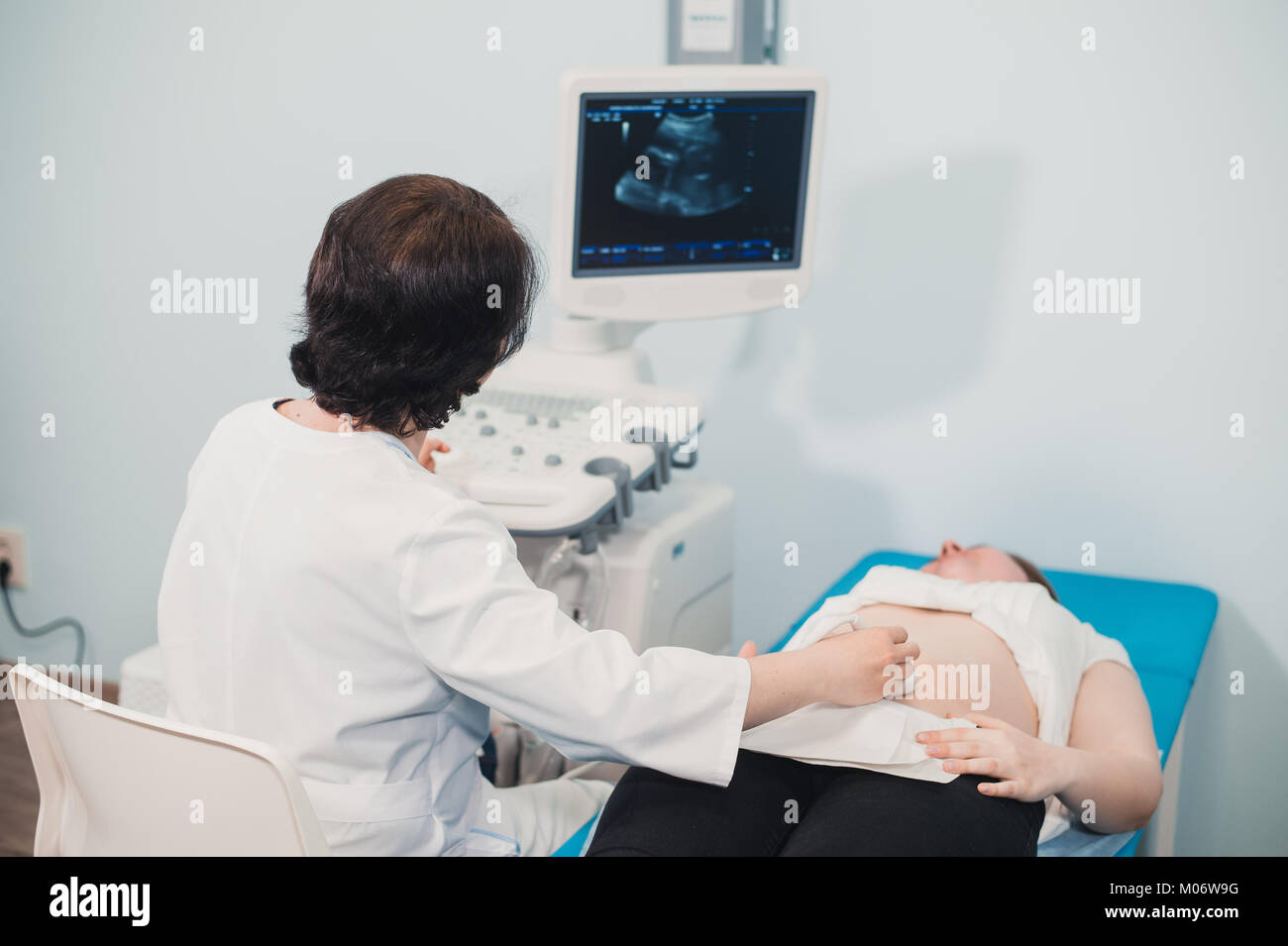 Doctor using ultrasound equipment screening hi-res stock photography ...