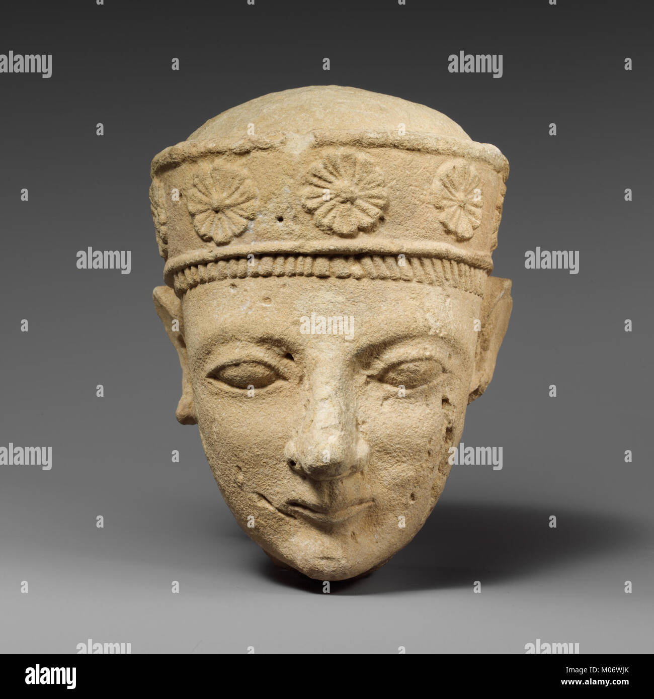 This limestone head depicts a beardless male with a diadem, reflecting ...