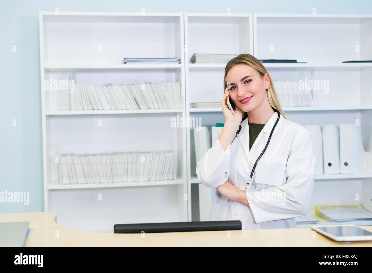 Portrait of a beautiful smiling nurse at desk station while talking on ...