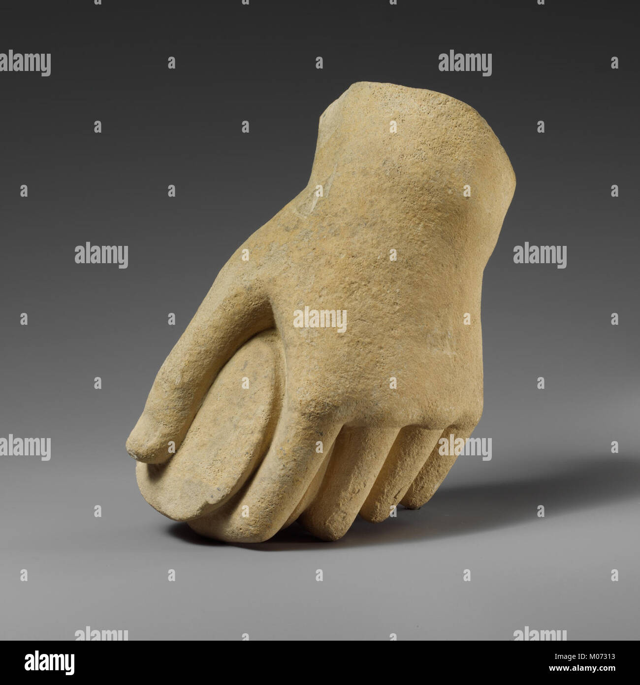 This limestone sculpture depicts a hand holding a pyxis, a small box or ...
