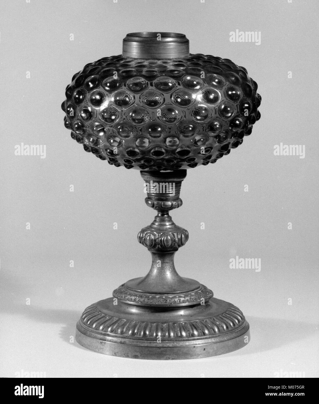 This hobnail lamp is a historical lighting device featuring a textured ...