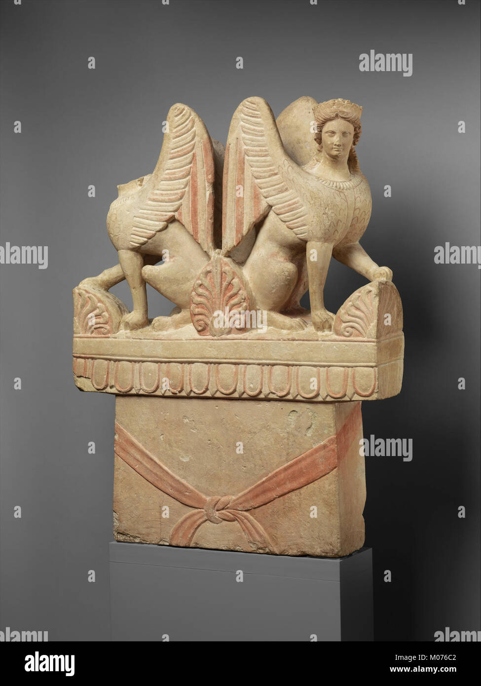 This limestone funerary stele features a shaft topped with two sphinxes ...