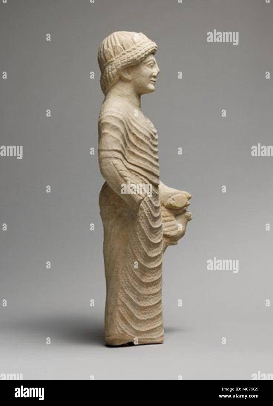 This limestone statue depicts a male votary holding a bird in his left ...