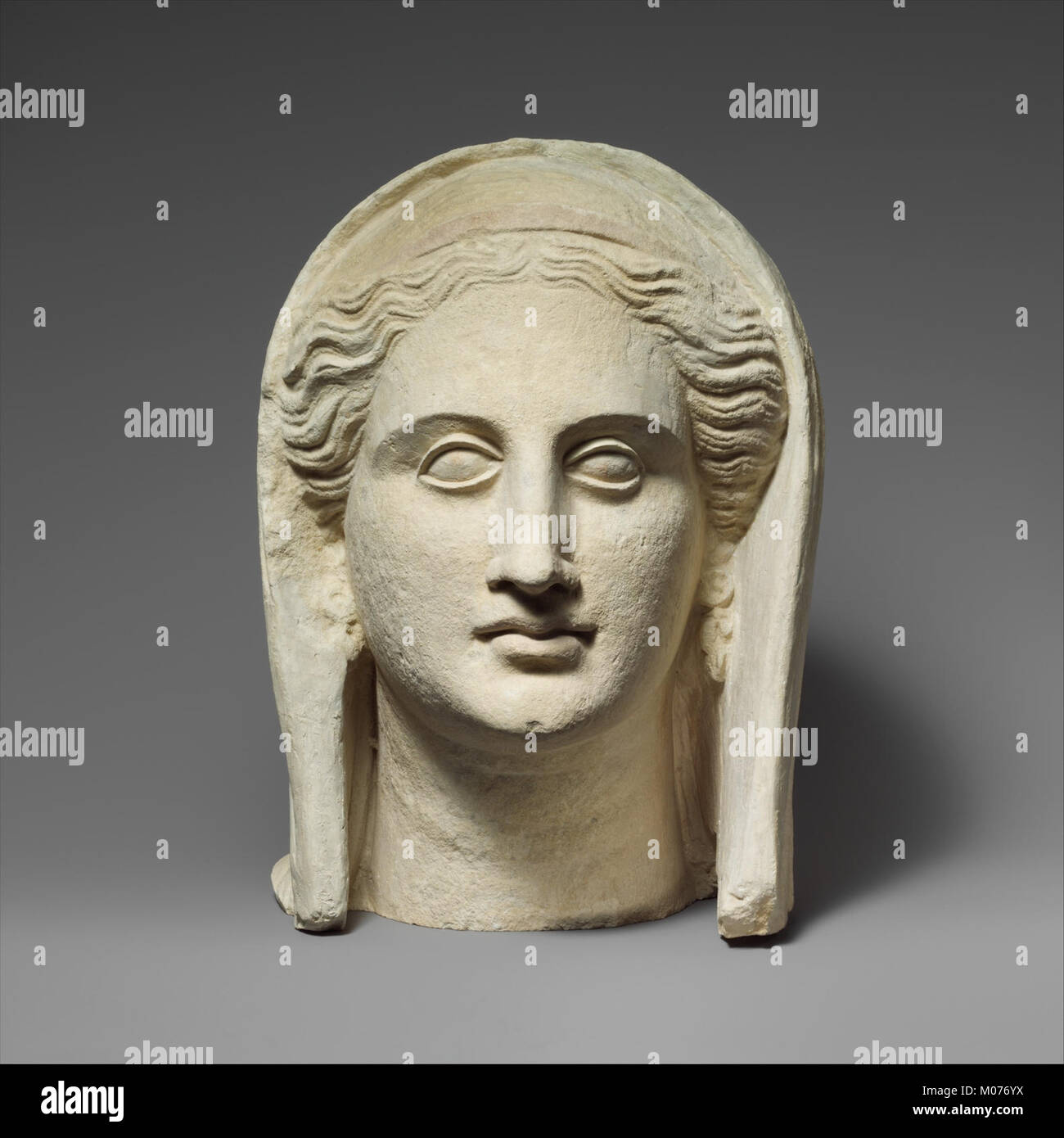 This limestone head depicts a veiled female votary, representing a ...