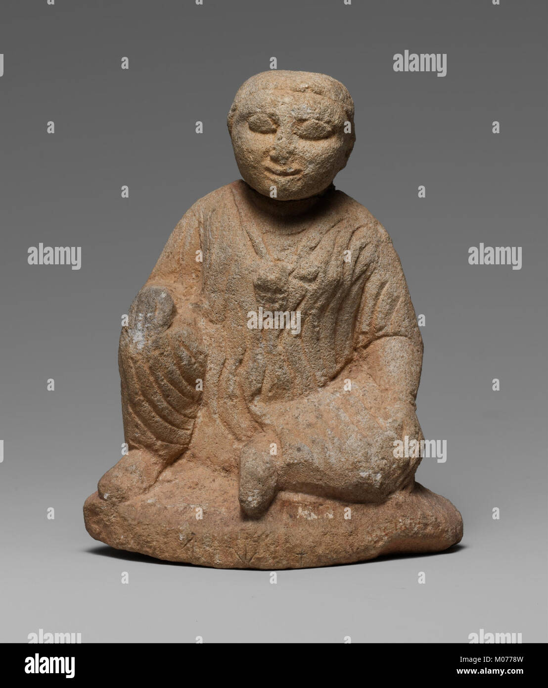 This limestone statuette features a seated temple boy, with detailed ...