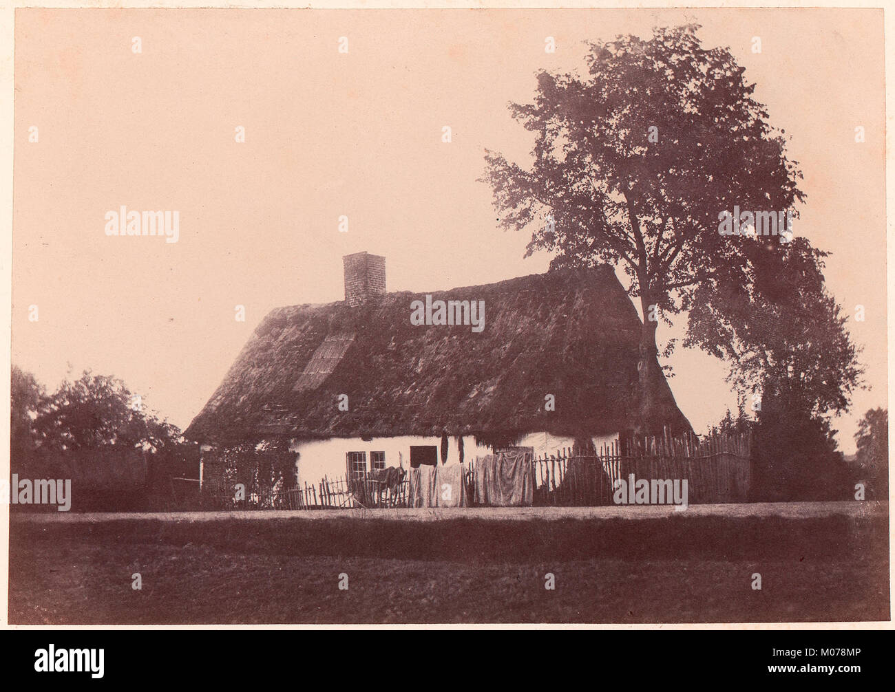 This artwork or photograph depicts a house with a thatched roof ...