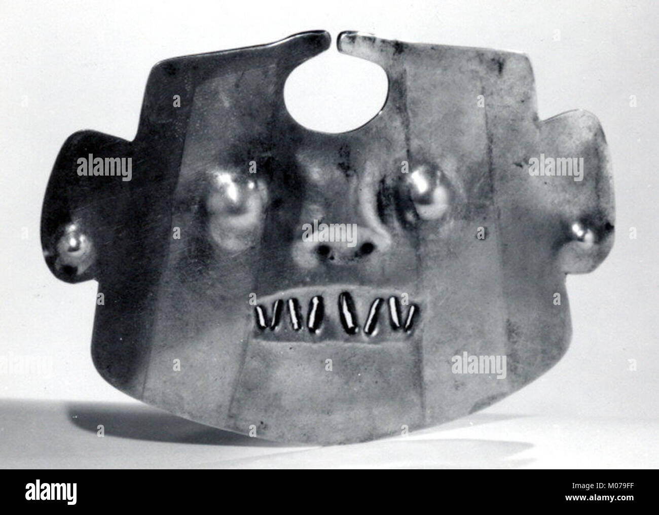 This nose ornament features a face motif and is an example of ...