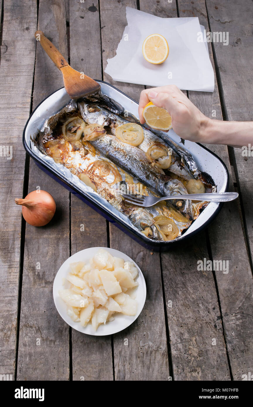 Mans hand squeezing lemon juice on mackerel fish Stock Photo - Alamy