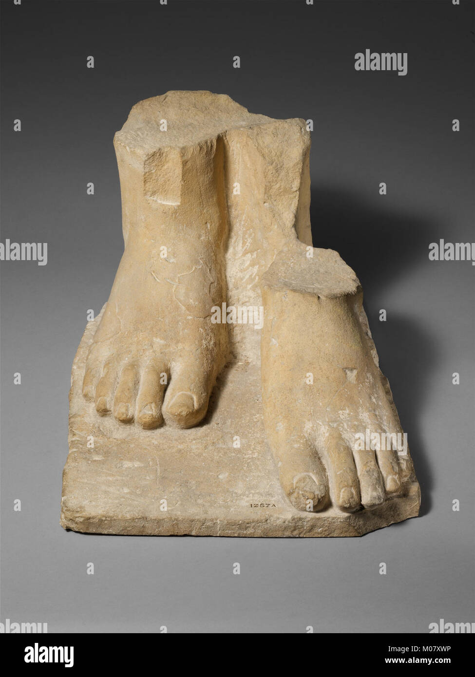 This limestone plinth displays the feet of a colossal male statue ...