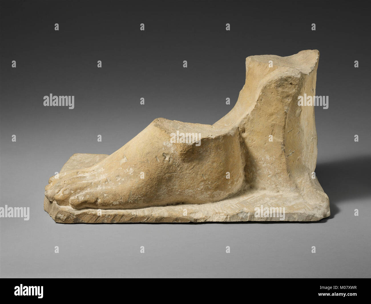 This limestone plinth supports the feet of a colossal male statue. It ...