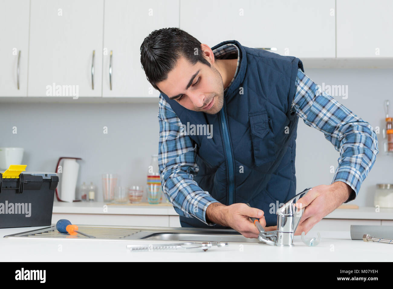 Plumber fitting tap in kitchen sink Stock Photo - Alamy