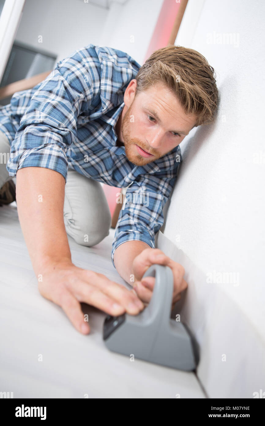 young handyman fitting carpet while installation Stock Photo - Alamy