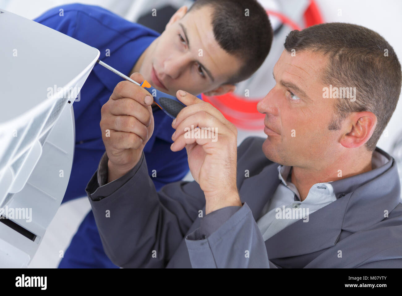 Two workmen carefully unscrewing screw Stock Photo - Alamy