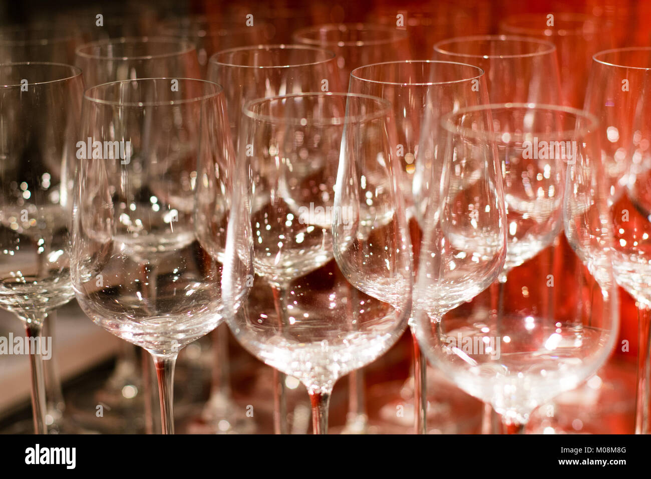 Many elegant wine glasses standing side by side. Background lighting ...