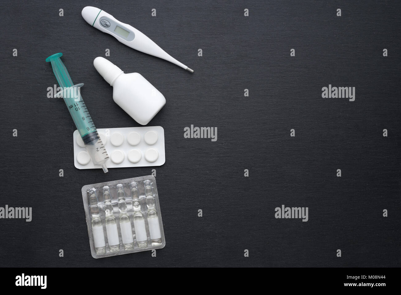 Thermometer, nasal drops tablets and ampoules with medicine on dark ...