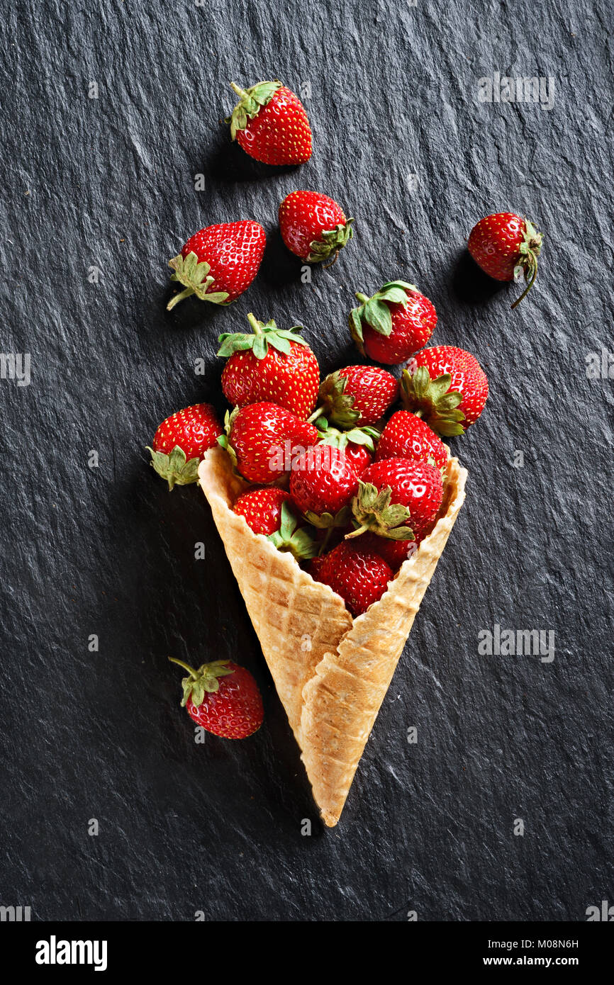 Strawberry explosion. Photo of strawberry in waffle cone on black slate ...