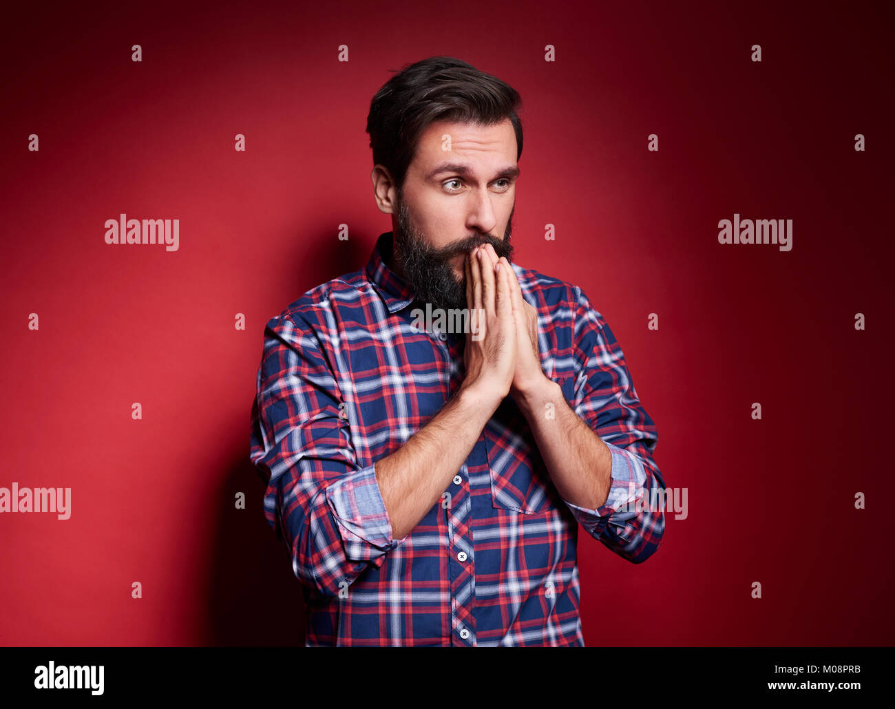 Worried man praying at studio shot Stock Photo - Alamy