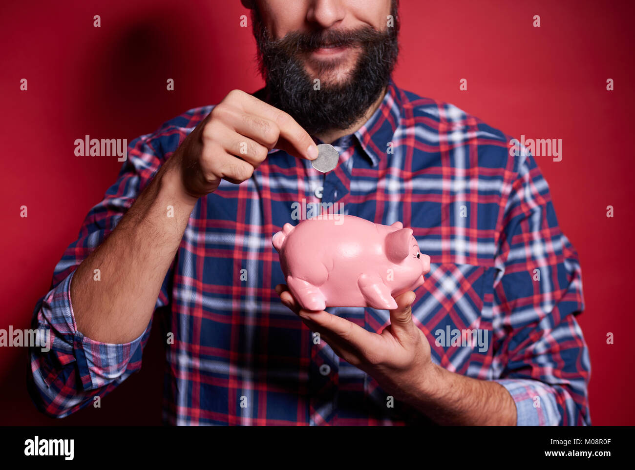 Unrecognizable man inserting coin into piggy bank Stock Photo - Alamy