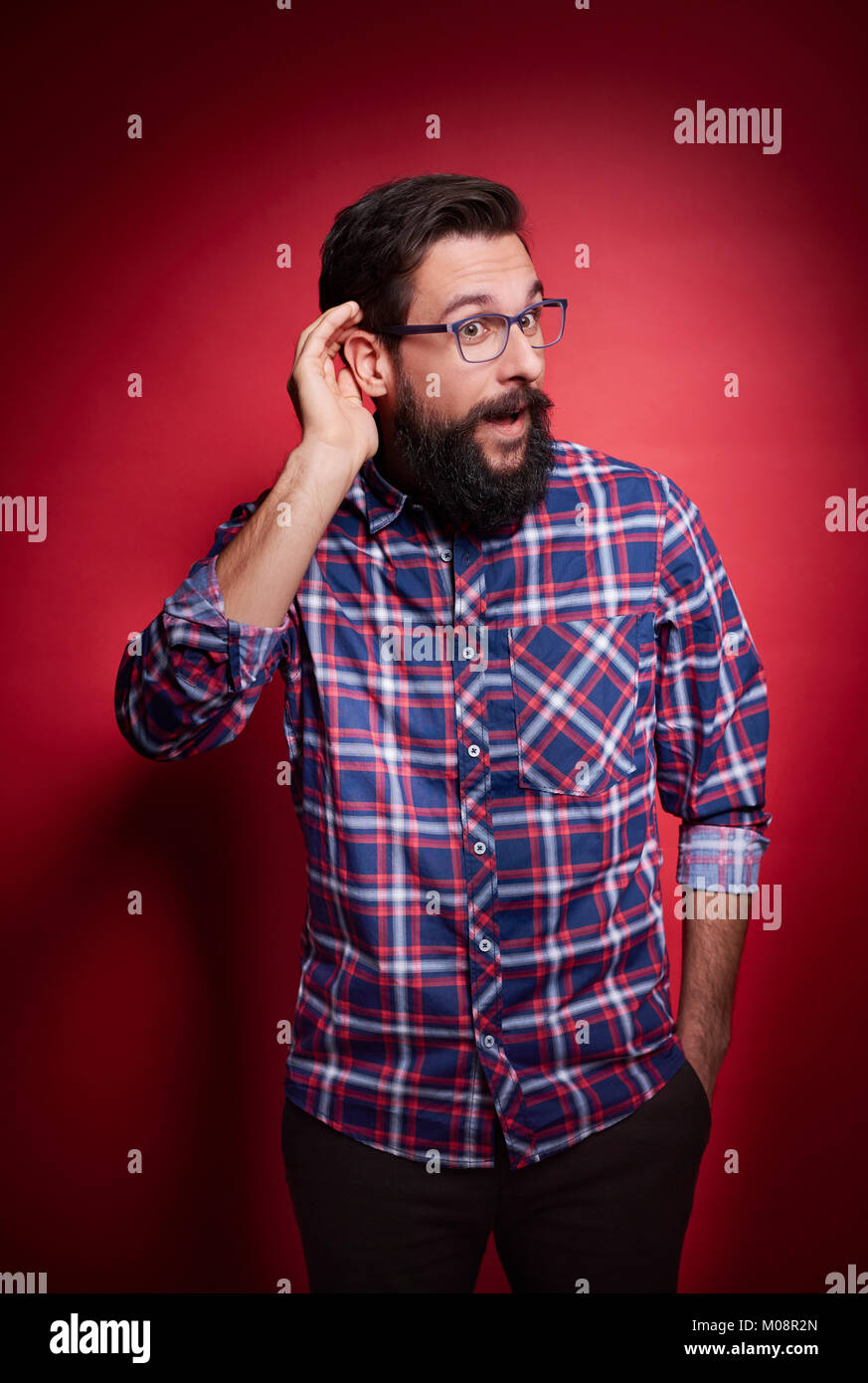 Surprised man eavesdropping at studio shot Stock Photo - Alamy