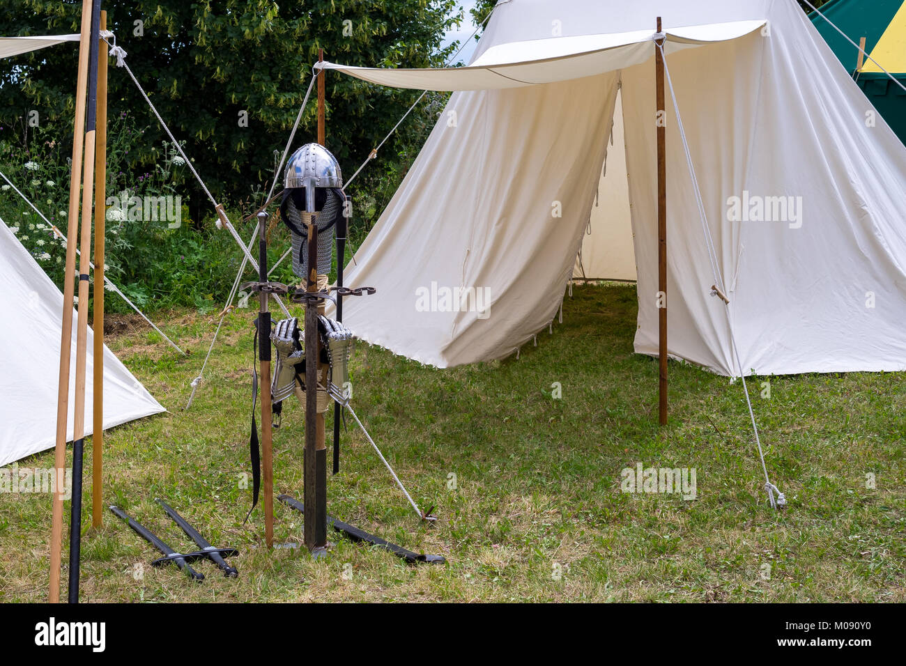 Knight camp with white tent. In the foreground iron helmet and chain ...