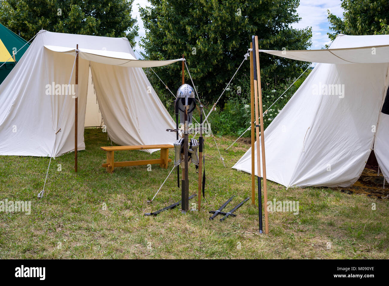 Knight camp with white tent. In the foreground iron helmet and chain ...