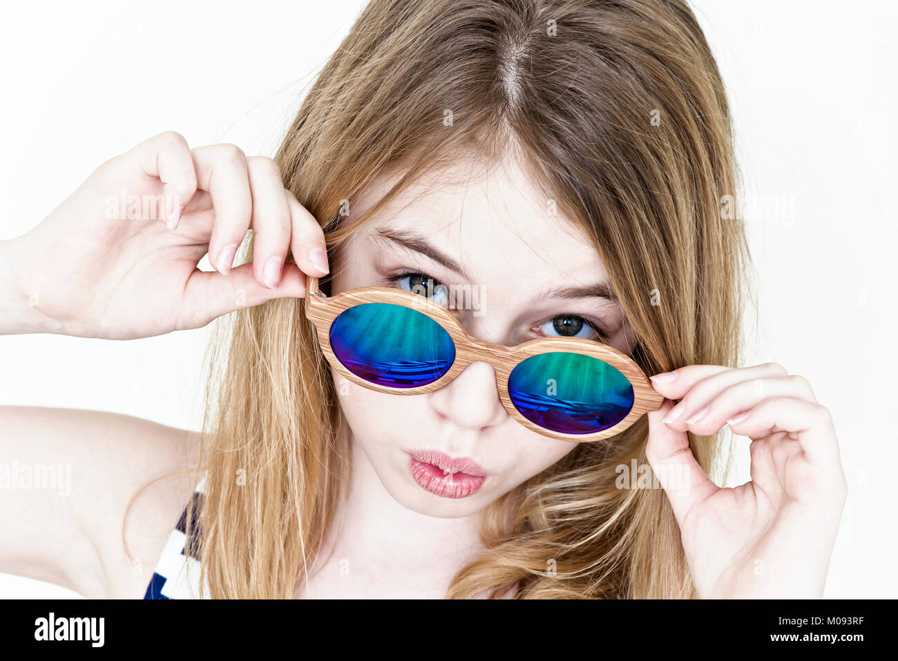 Girl eleven years old standing near white wall with green sunglasses ...