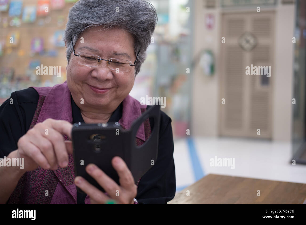 asian elder woman holding mobile phone in department store. elderly ...