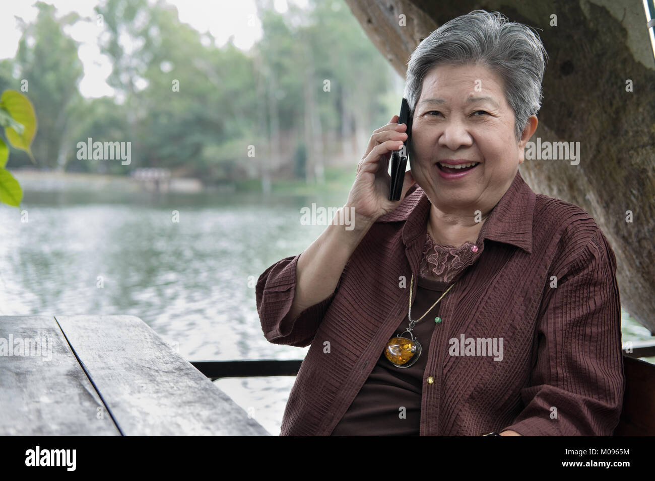 elder woman talk on mobile phone in garden. elderly female speaking on ...