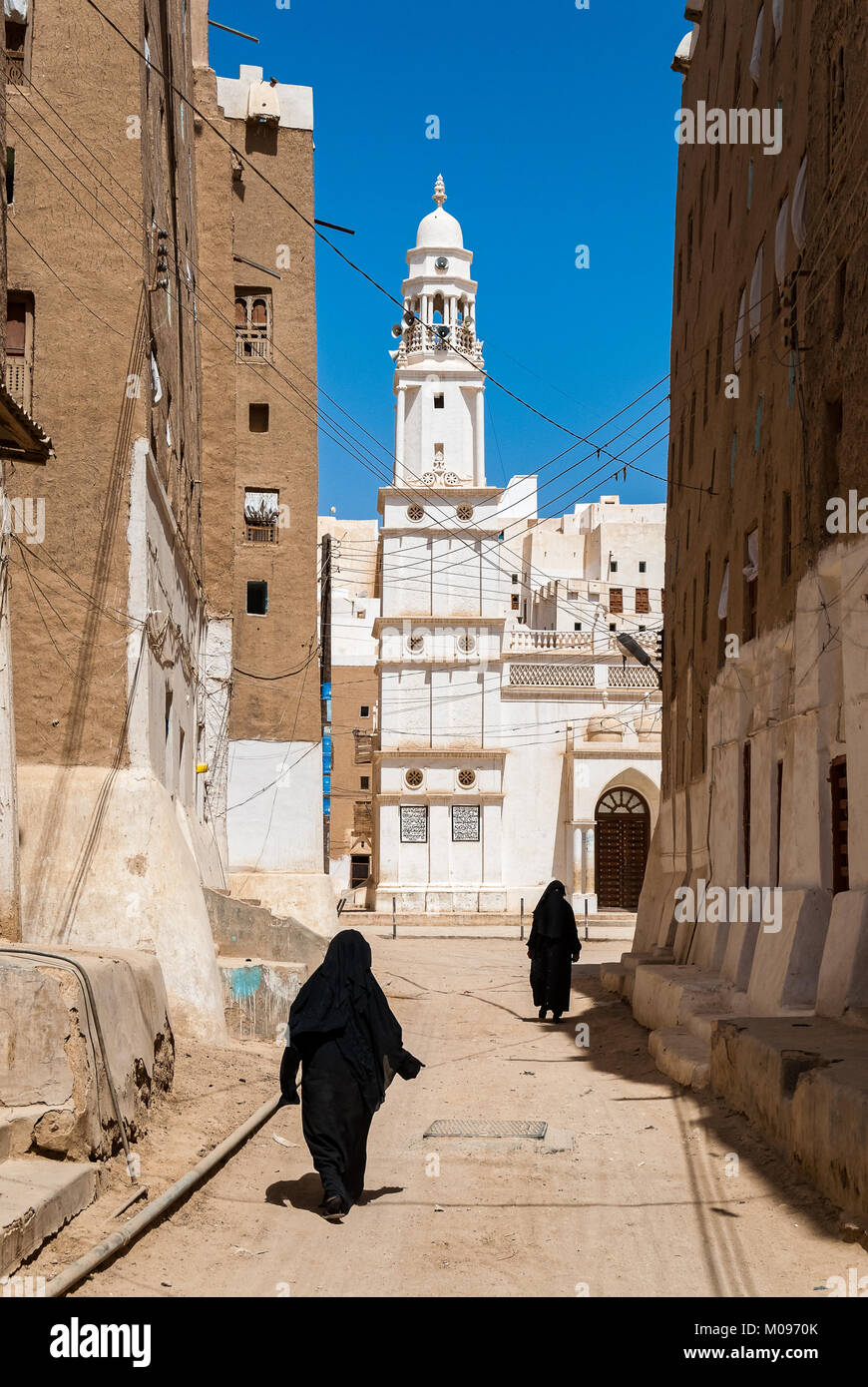 Two women dressed in black walk in a street of Shibam, a UNESCO World ...