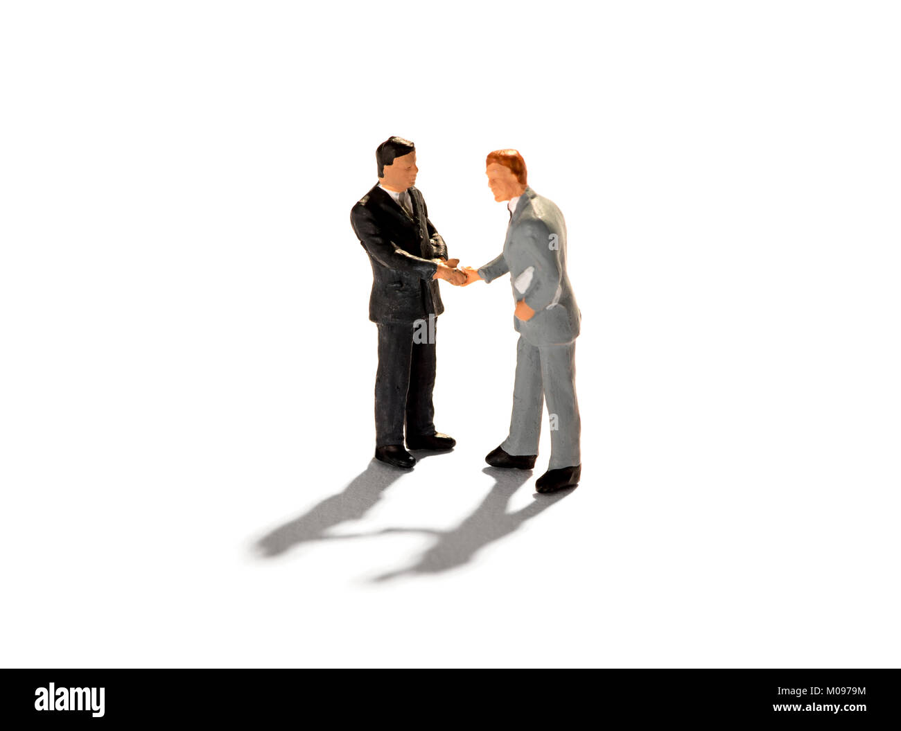 Two miniature figures of businessmen shaking hands as they clinch a ...
