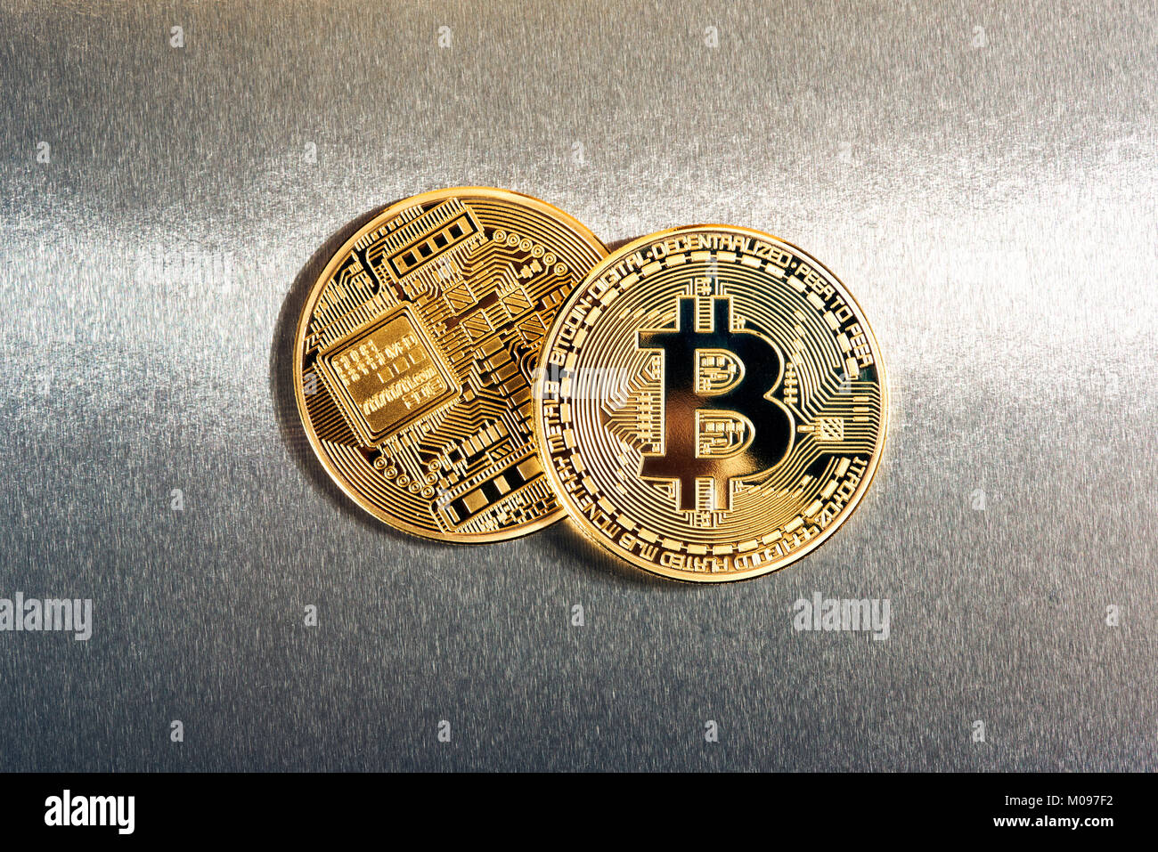 Two gold Bitcoins on a reflective metallic silver background with copy ...