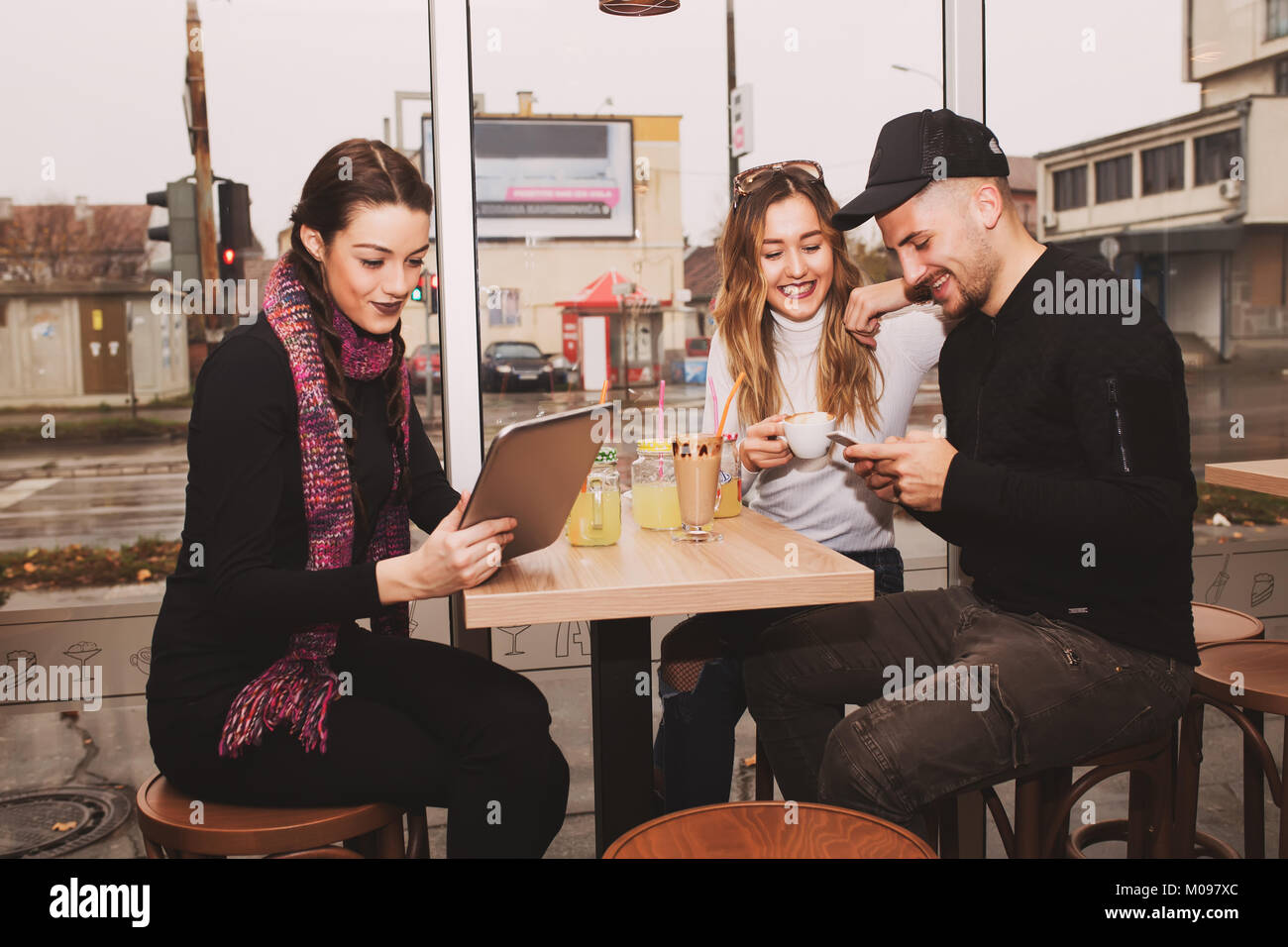 Cheerful group of friends, one man and two women sitting at the table ...