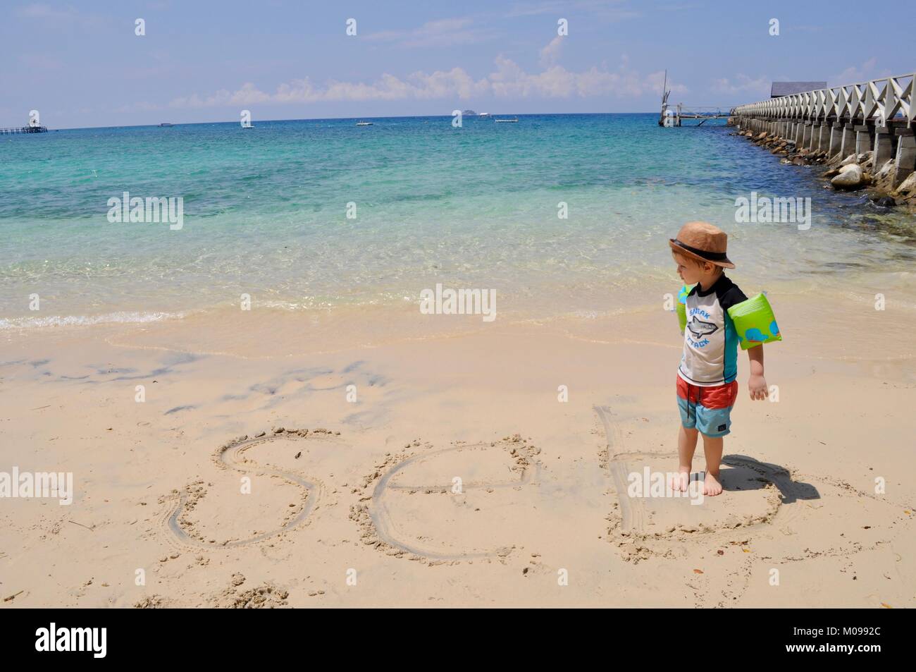 Small boy with armbands and name Seb written in sand on the beach at ...
