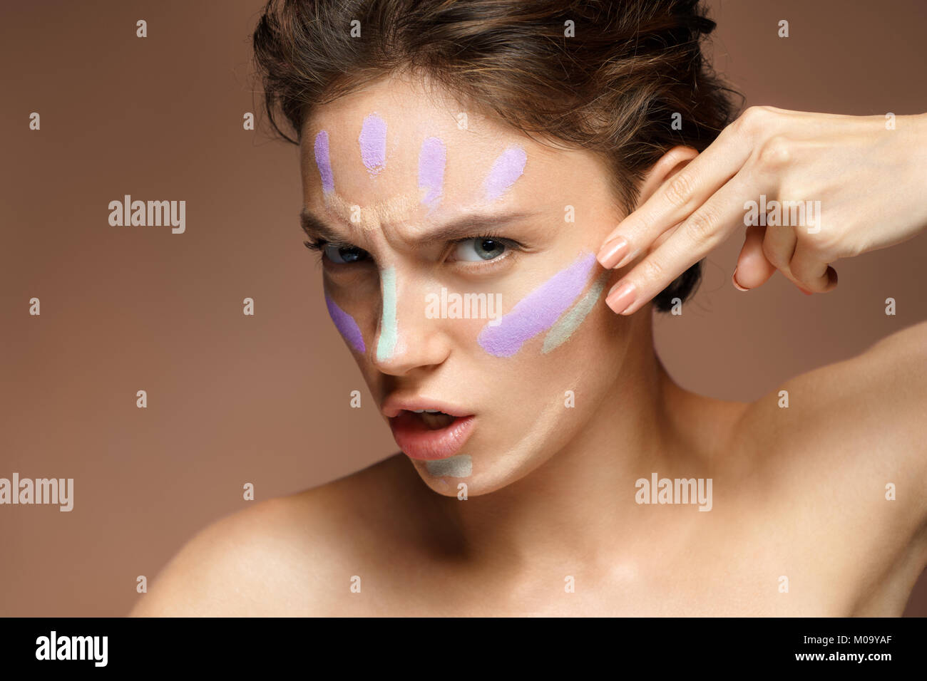 Resolute woman doing makeup using concealer. Photo of beautiful ...