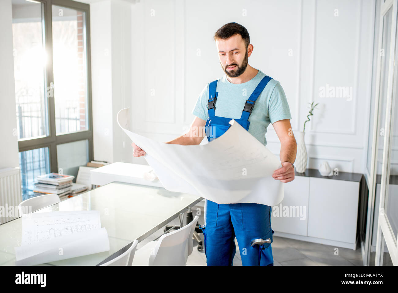 Repairman with paper drawings at the office Stock Photo - Alamy