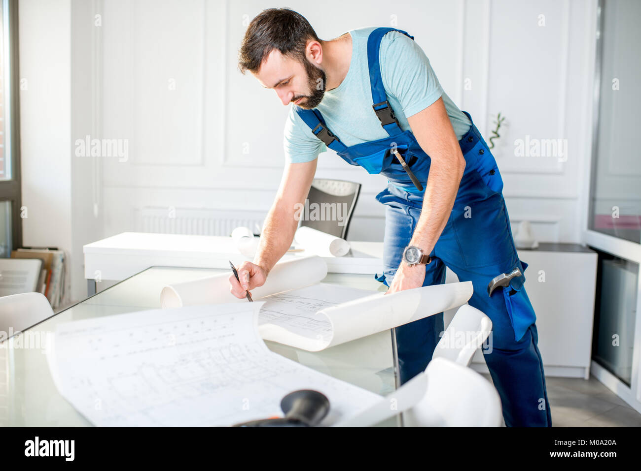 Repairman with paper drawings at the office Stock Photo - Alamy