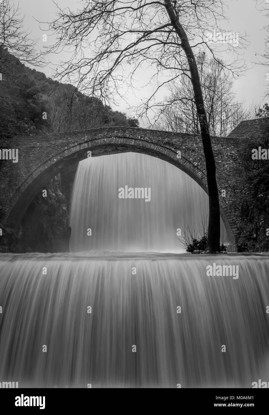 Beautiful cascading waterfalls under an old traditional stone bridge in ...