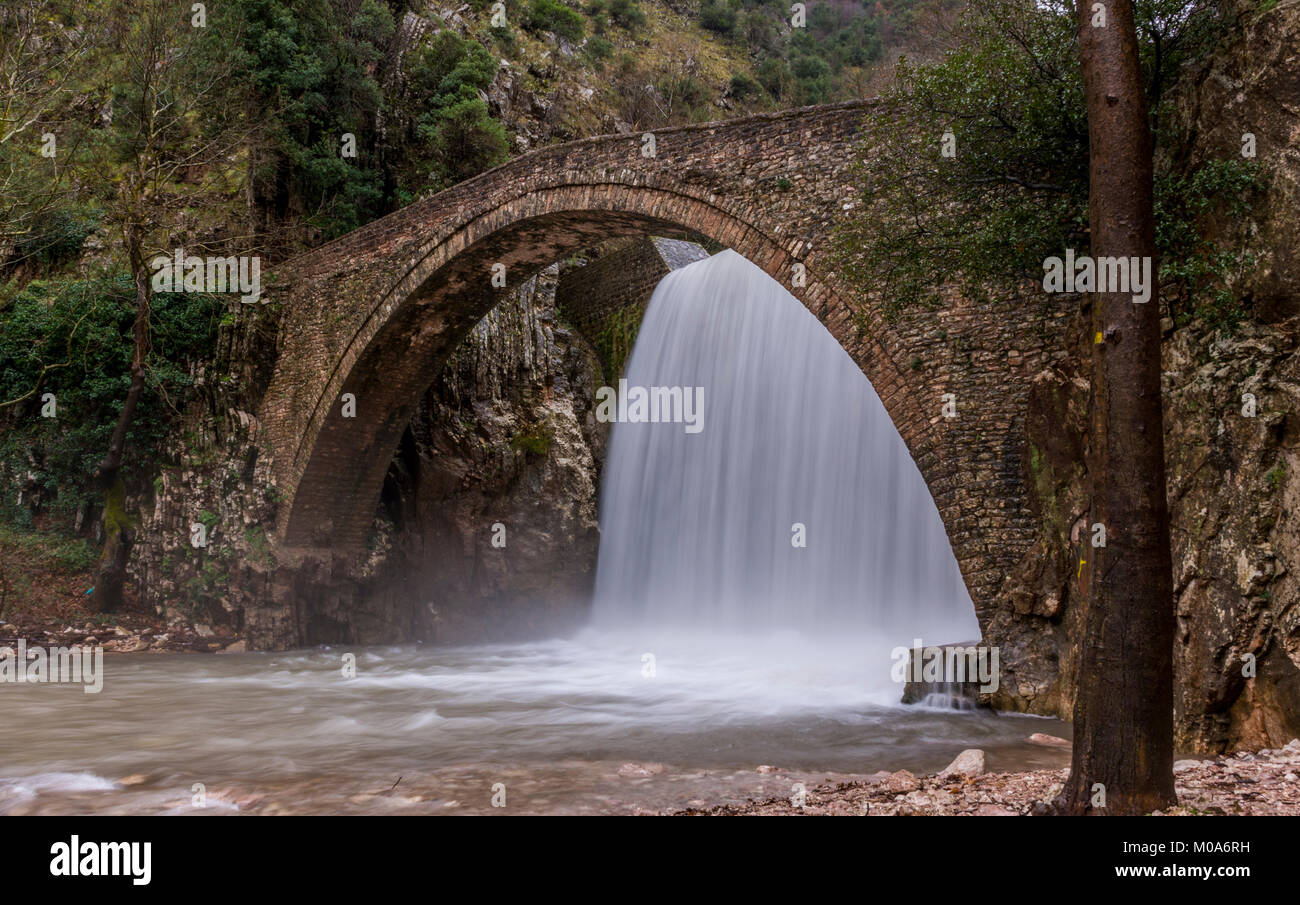 Beautiful cascading waterfalls under an old traditional stone bridge in ...