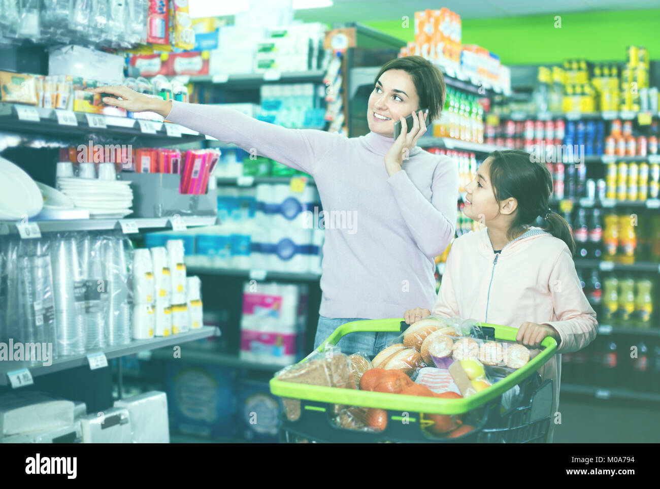 Young smiling glad friendly female shopper talking on phone being with ...
