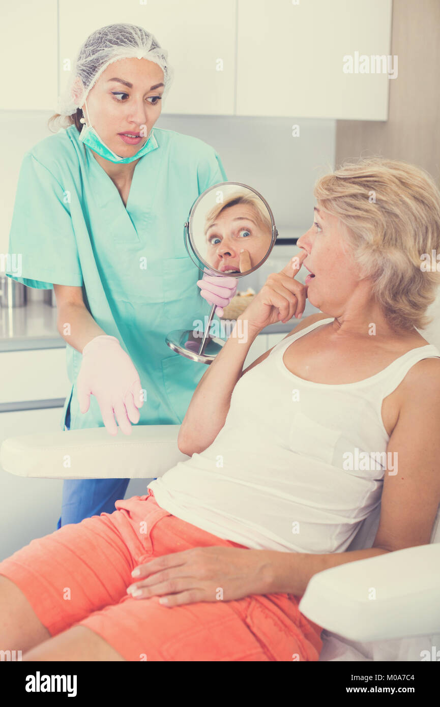 Portrait of unhappy worried woman visiting clinic of esthetic medicine ...