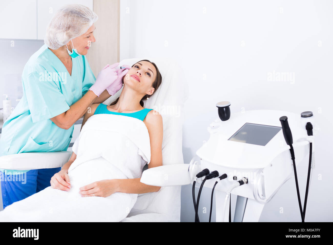 Young woman getting injection for facial correction procedure in ...