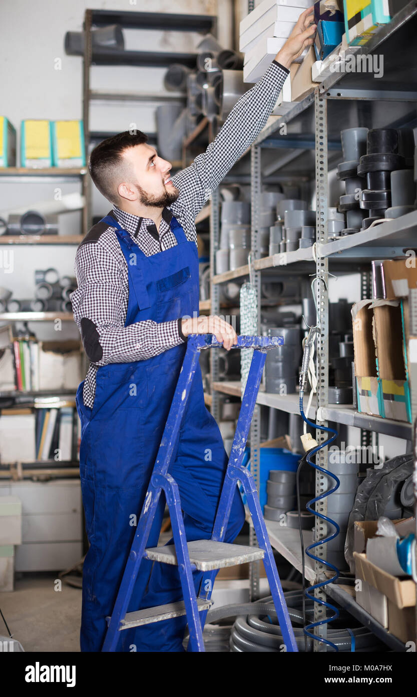 Young smiling european male worker showing his workplace at workshop ...