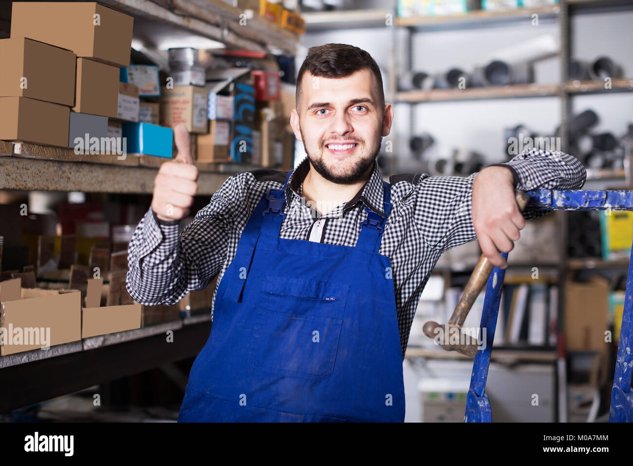 Smiling worker demonstrates a neat warehouse for parts in his workplace ...