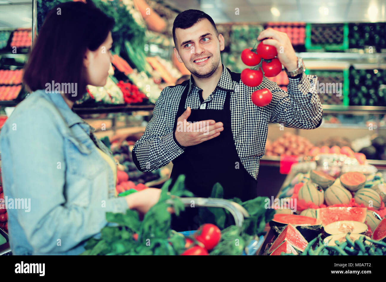 Smiling male seller assisting customer to buy fruit and vegetables in ...