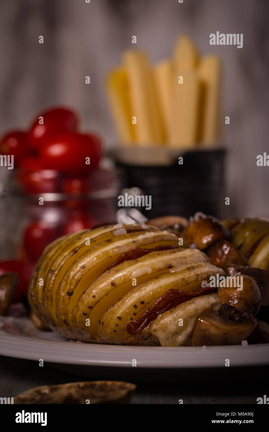 Vertical photo of two roasted whole potatoes on white plate. The ...
